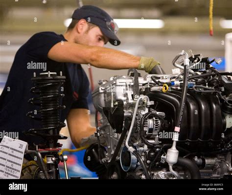 A Worker At Toyota Final Assembly Production Line Fits A Part To A