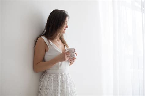 하얀 드레스를 입은 중년 여성 집에서 커피를 마시고 창 밖으로 바라보는 것 가정 생활에 대한 스톡 사진 및 기타 이미지 가정