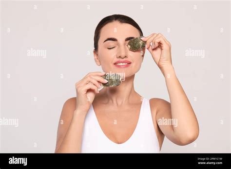 Beautiful Woman Applying Green Tea Bags On Skin Under Eyes Against