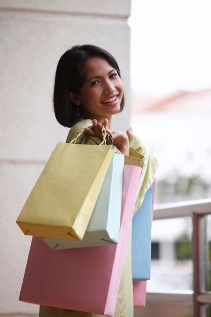 Premium Photo Woman Holding Shopping Bags While Standing In Corridor