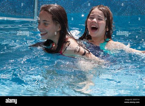 Two Girls Having Fun Together And Laughing In An Outside Swimming Pool