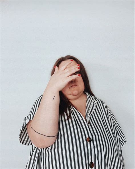 A Woman Covers Her Eyes With Her Hands While Standing Against A White