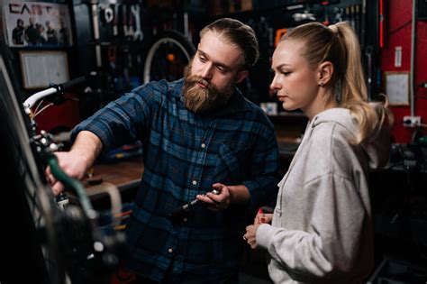 금발의 여성 고객과 대화를 나누는 사이클링 수리공이 수리점에서 진단 중에 감지된 자전거의 문제에 대해 이야기한다 기계공에 대한 스톡 사진 및 기타 이미지 Istock