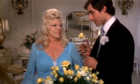 A Man Standing Next To A Woman In A Blue Dress