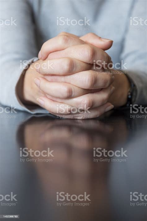 Womans Hands With Fingers Interlocked Expressing Power On Dark Table