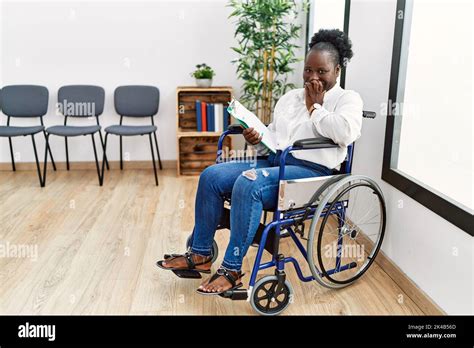 Young Black Woman Sitting On Wheelchair At Waiting Room Laughing And