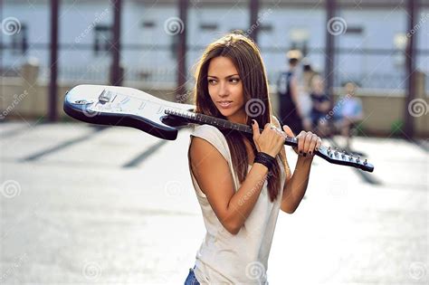 Привлекательная молодая женщина с гитарой внешним портретом моды Стоковое Фото изображение