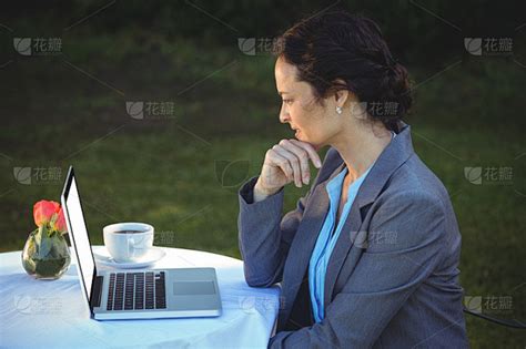 女商人一边喝咖啡一边用笔记本电脑