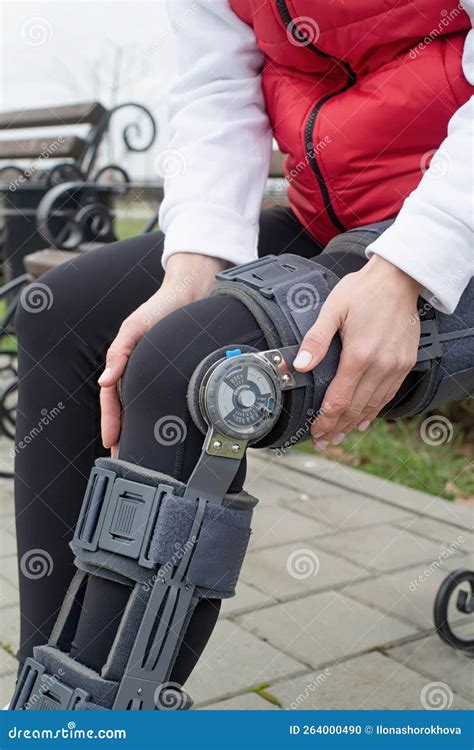 Woman Wearing Knee Brace Or Orthosis After Leg Surgery Walking In The