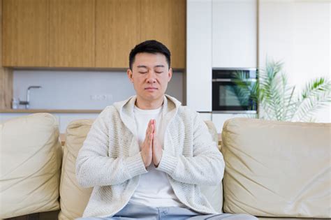 집에서 혼자 기도하는 젊은 아시아 남자 남성 접이식 연필 팔과 아파트 방에서 명상 기독교 종교 는 그들의 희망에 대한 전통적인