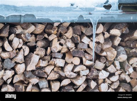 Stack Of Wood Arranged To A Wall Icicle Hanging Down From The Rainwater Gutter Stock Photo Alamy