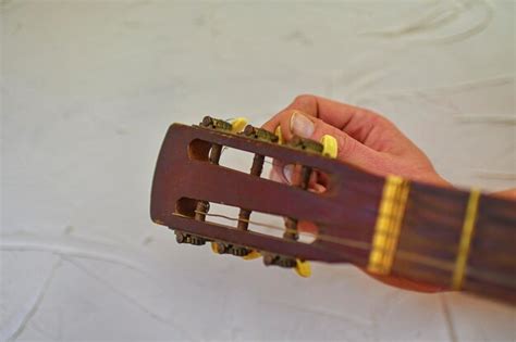 Premium Photo Fingers Turning The Tuning Pegs And Gears Of The Headstock Of An Acoustic Guitar
