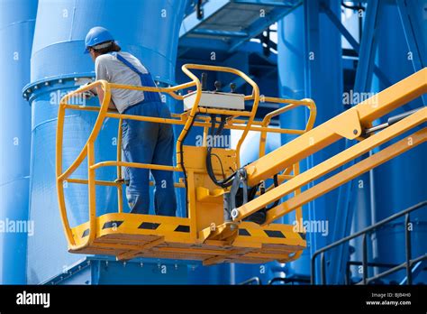 Construction Worker In Cherry Picker Working On Industrial Plant Stock