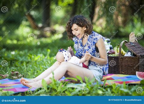 Young Beautiful Mother Sits With Her Daughter On Blanket In Park Stock