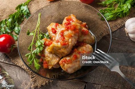 삶은 양배추 롤의 한 부분은 검은 유리 판에 쌀과 고기로 채워진 것 중 하나이며 금속 포크는 채소 근처의 채소와 소박한 나무 테이블위에 있습니다 갈색에 대한 스톡 사진 및