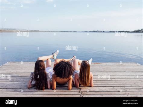 Funny Multiracial Teenage Girls Lie On A Wooden Floor Outdoors