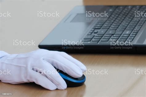 흰색 섬유 장갑을 끼고 나무 테이블에 노트북 키보드 옆에 컴퓨터 마우스를 들고 있습니다 장갑에 대한 스톡 사진 및 기타 이미지