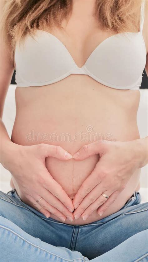 Pregnant Woman Holding Stomach In Heart Shape Gesture With Hands On Her