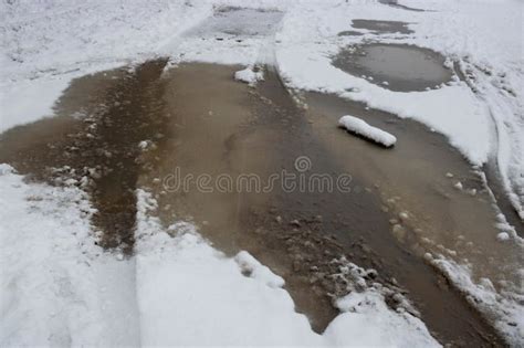 The Snow Thaw There Is A Muddy Puddle With Snow On The Road Stock