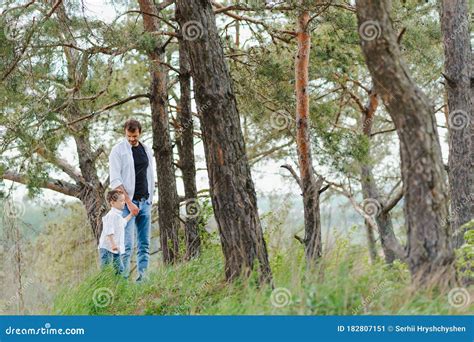 Padre Feliz E Hijo Sentados En El Parque Un Joven Sonriente Pasando Tiempo Con Su Hijo Imagen