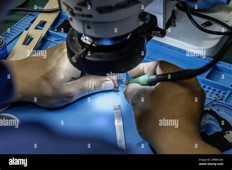 The Hands Of An Electronic Repair Shop Operator Under An Electron Microscope Soldering Some
