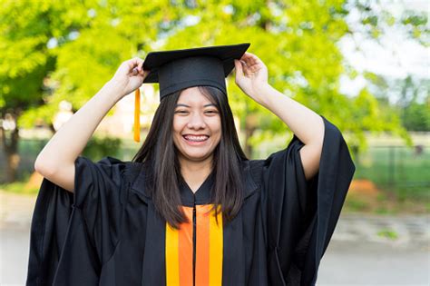 졸업식에서 졸업 후 검은 색 아카데믹 가운과 모자를 쓰고 졸업식에서 즐거운 순간을 가진 학위 증서를 소지하고 있는 여성 대학