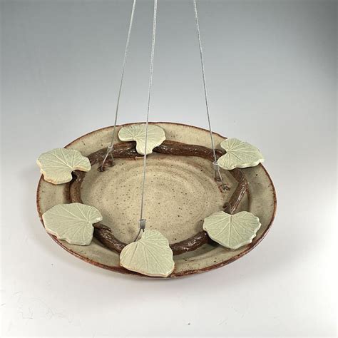 A Bowl With Leaves Hanging From Its Sides And Two Strings Attached To