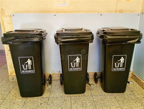Three Dark Colored Trash Cans Are Lined Up Neatly With Black Trash Bags