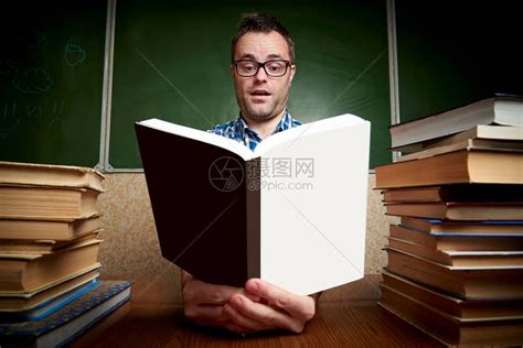 惊讶的蓬头垢面的疲惫的胡子拉碴的年轻人戴着眼镜在桌子上看书高清图片下载 正版图片505627473 摄图网