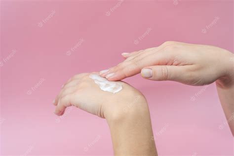 Premium Photo Female Hands Rubbing The Cream On Pink Background