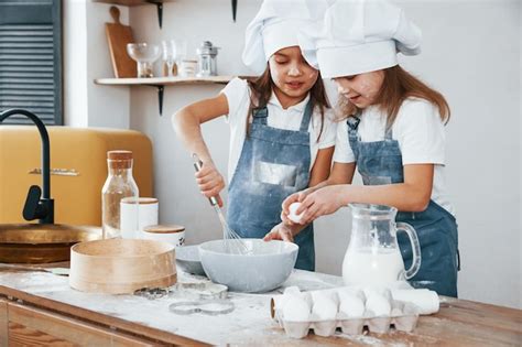 Dos niñas con uniforme de chef azul mezclando comida en la cocina
