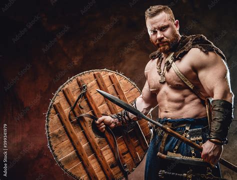 Nordic Warlike Barbarian With Muscular Build And Naked Torso Holding
