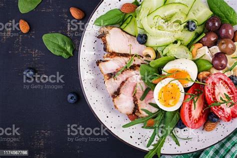 케톤 생성 식단 케토 브런치 삶은 달걀 돼지 고기 스테이크와 올리브 오이 시금치 브리 치즈 견과류와 토마토 맨 위 보기 개념에