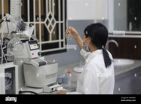Vietnamese Woman Scientist Checking Laboratory Glass Flask To Make An Experiment In The