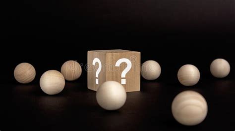 Wooden Cube With A Question Mark Surrounded By Wooden Balls On A Black