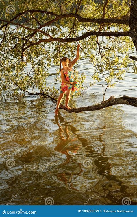 La Jeune Fille Se Tient Sur Une Branche D Un Arbre Au Dessus De L Eau D