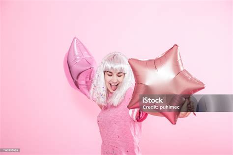은색 머리를 가진 재미 있는 소녀는 분홍색 배경에 미소와 감정을 제공 합니다 풍선 및 색종이와 젊은 여자 또는 십 대 소녀
