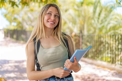 Jeune étudiante blonde à l extérieur regardant en souriant Photo Premium