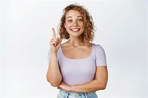 Ragazza Bionda Felice Che Punta Il Dito Verso L Alto Sorridente E Sembra Eccitata Mostrando