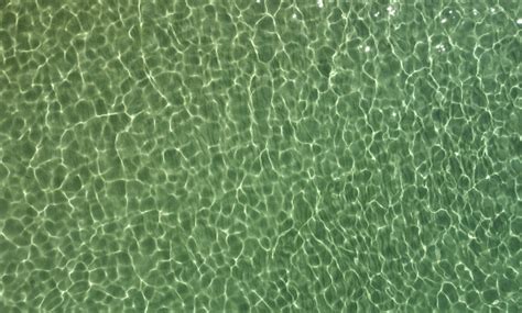 돌과 자갈이 깔린 투명한 바다 전망 표면의 태양 눈부심은 맑은 에메랄드 빛으로 바람에 흔들립니다 자연스러운 여름 바다 배경 질감 0명에 대한 스톡 사진 및 기타 이미지