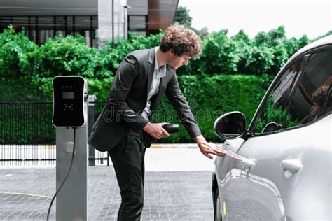 Progressive Businessman Charging Ev Car At Public Parking Car Charging