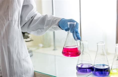 Scientist In A Laboratory Holding A Volumetric Flask Containing A