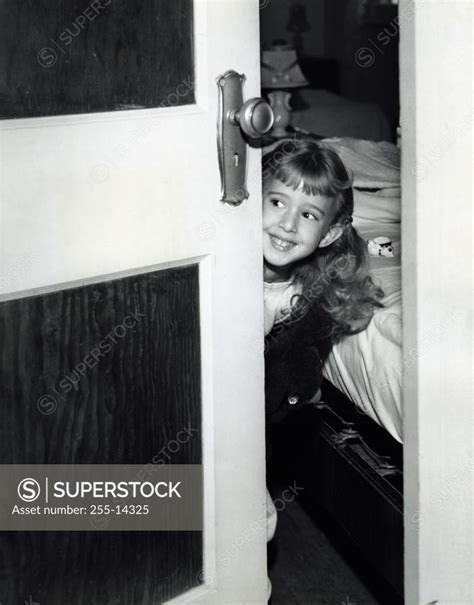 Girl Peering Around Bedroom Door Superstock