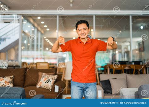 Male Shop Assistant Smiling With Hand Gesture Pointing Down In