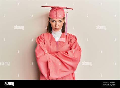 Mujer joven caucásica con gorra de graduación y túnica de ceremonia