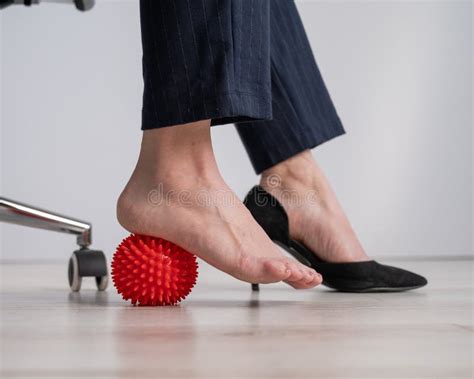 Business Woman Massages Her Feet On A Massage Ball With Spikes Stock
