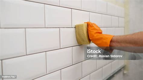 세라믹 타일 놓기 마스터는 특수 스폰지로 이음새를 닦습니다 스폰지로 남성 손으로 타일 벽을 청소하십시오 남성의 손은 스폰지로 세라믹 타일을 닦습니다 가구에 대한 스톡 사진