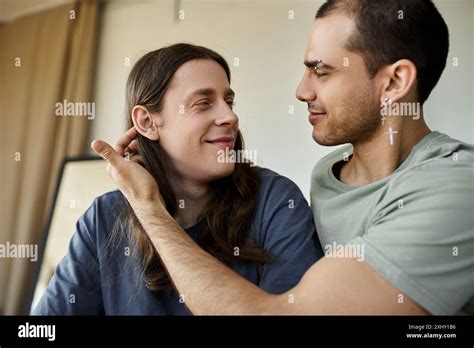 A Young Gay Couple Share A Tender Moment In Their Bedroom Gazing Into
