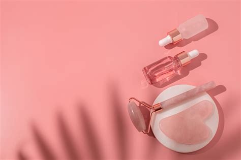 분홍색 배경에 화장품 액체 투명 젤의 석영 롤러와 핑크 유리 병을 마사지하십시오 공간을 복사합니다 드롭퍼 병 히알루론산 오일 세럼 얼굴 마사지와 휴식 과샤 건강관리와 의술에