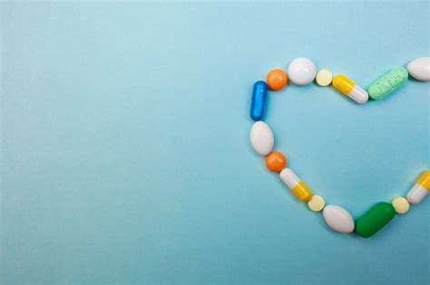 다 색된 정제와 하트 모양의 캡슐 정제 파란색 배경 질병에 대 한 진통제에 제약 의학 환 약에 대 한 백색 병 0명에 대한 스톡